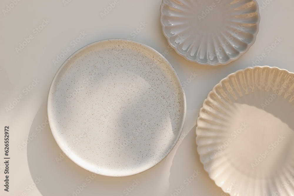 Three different size stoneware plates on beige table background. Flat ...