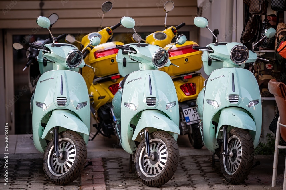 mopeds scooters parked in a row on a street. gas, rechargeable, battery ...