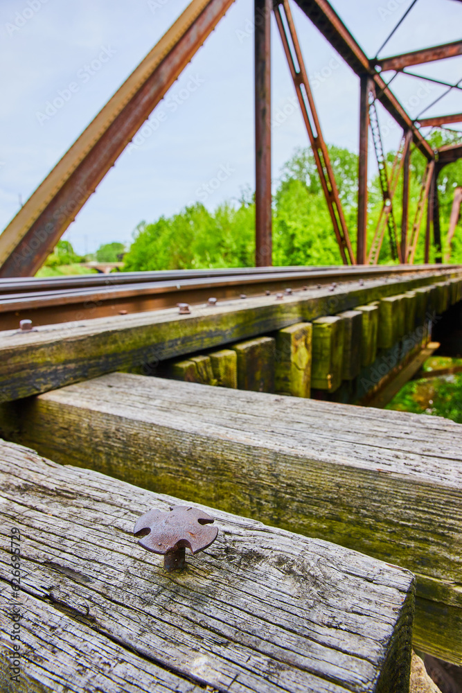 Cross shaped nail sticking out of wooden beam on long truss iron metal ...