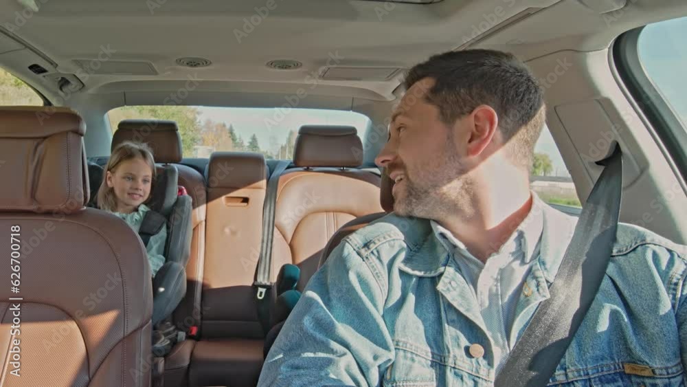 Adult man driving car with little teen daughter at back seat. Close up ...