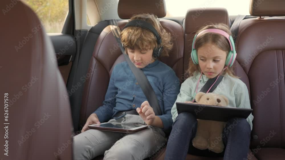 Portrait of little cute boy and girl sitting in backseat of car while ...