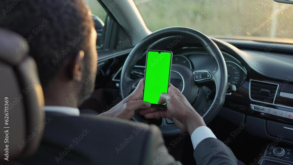 Portrait of business man driving car, using modern gadget, looking at ...