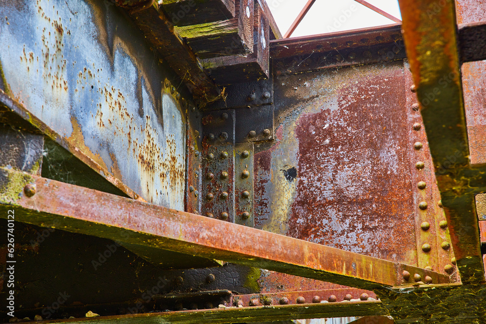 Underside railing of old rusting metal corroding railroad bridge with ...