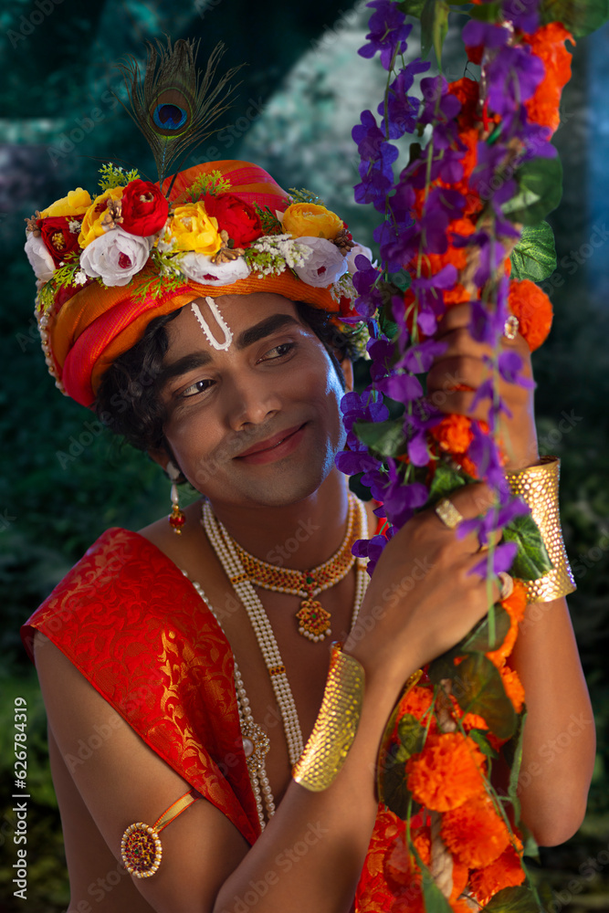 Young man dressed up as Lord Krishna and sitting on a swing on the ...