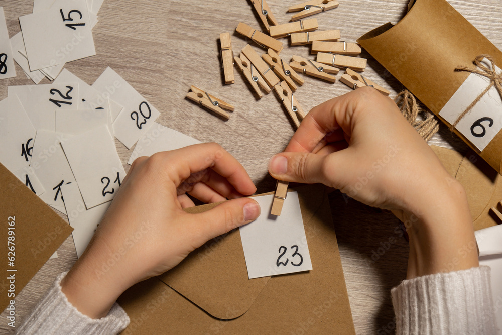 Unrecognizable young woman sticks number on craft bag, fastens with ...
