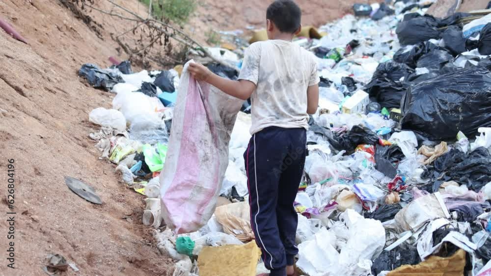 A poor boy collecting garbage waste from a landfill site in the ...
