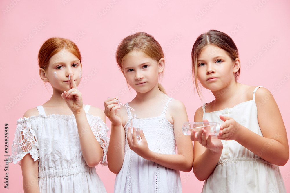 Beautiful little girls applying face cream, taking care after skin with ...