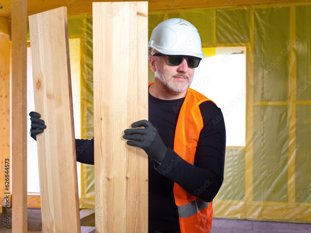 Foto de Man builder. Loader with boards. Worker is building house ...