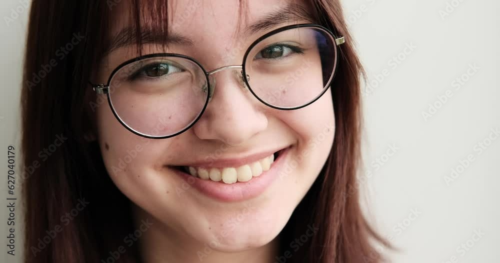 In a close-up portrait, a teenage girl's face fills the frame, adorned ...