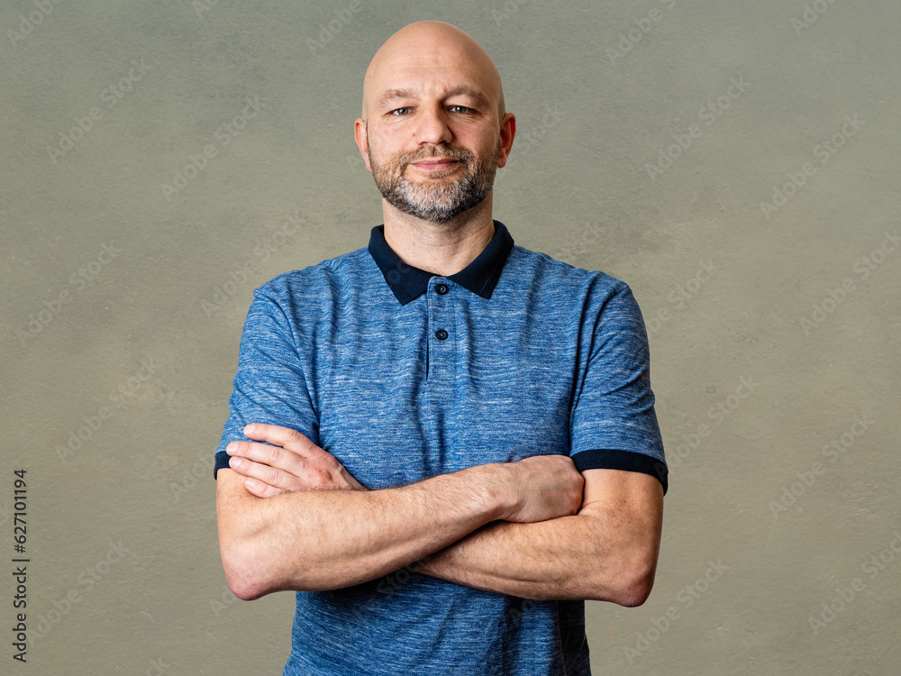 Portrait of a bald man in blue shirt on a light color background. The ...