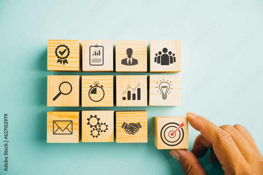 Hand arranging wood block stacking on a blue background, symbolizing ...