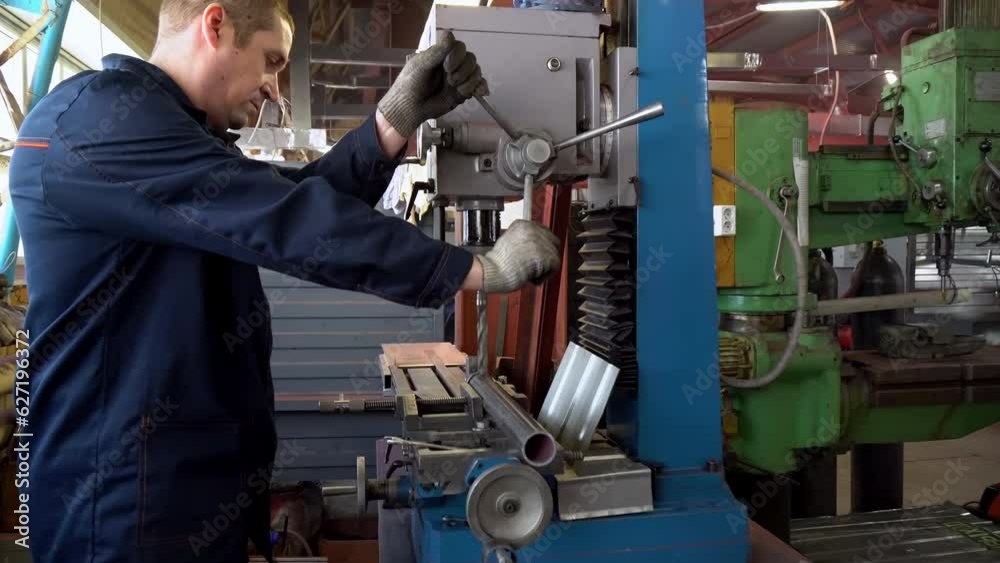 Worker is operating the industrial drill at the manufacturing facility ...