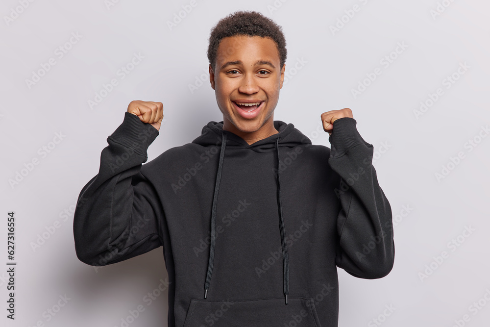 Cheerful dark skinned guy with fists clenched in celebration his ...