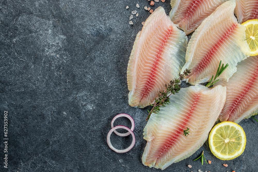 raw Tilapia fish, skinless meat on a dark background. banner, menu ...