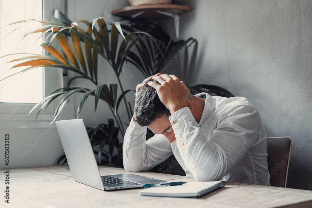 Unhappy young Caucasian male worker in glasses look at laptop screen ...