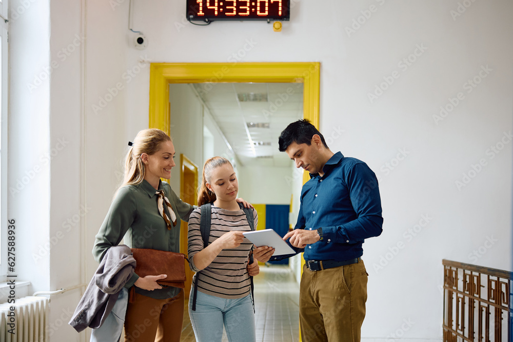 High school teacher using touchpad with his student and her mother in ...