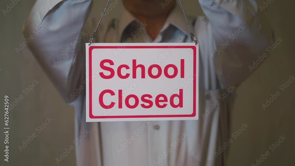 School Closed sign. A man hangs a school closed sign on the door of a ...