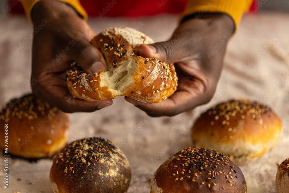 African american male baker in bakery kitchen ripping fresh rolls Stock ...