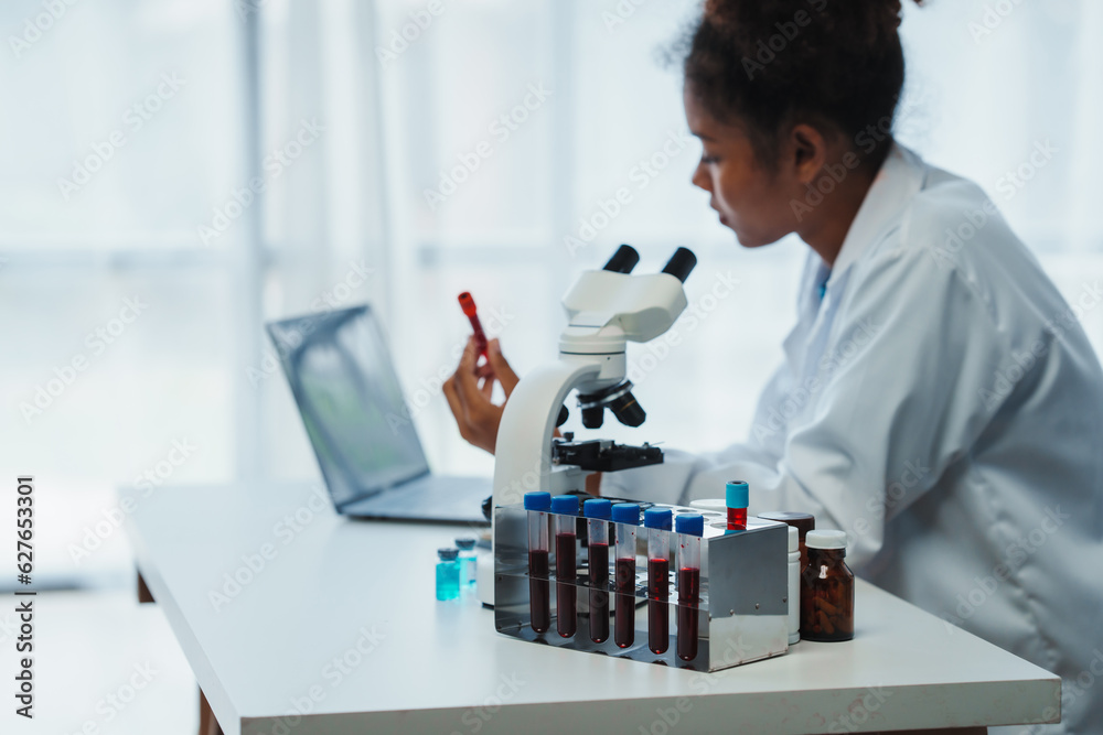 African American female technician testing blood sample in lap. blood ...