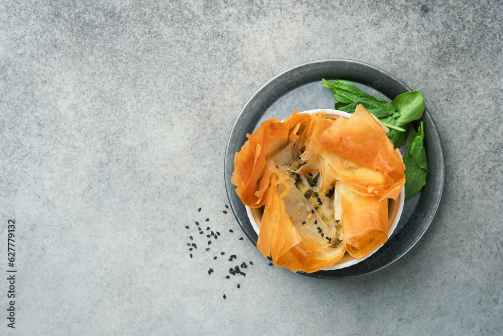 Filo pies with soft feta cheese and spinach in ceramic molds on old ...
