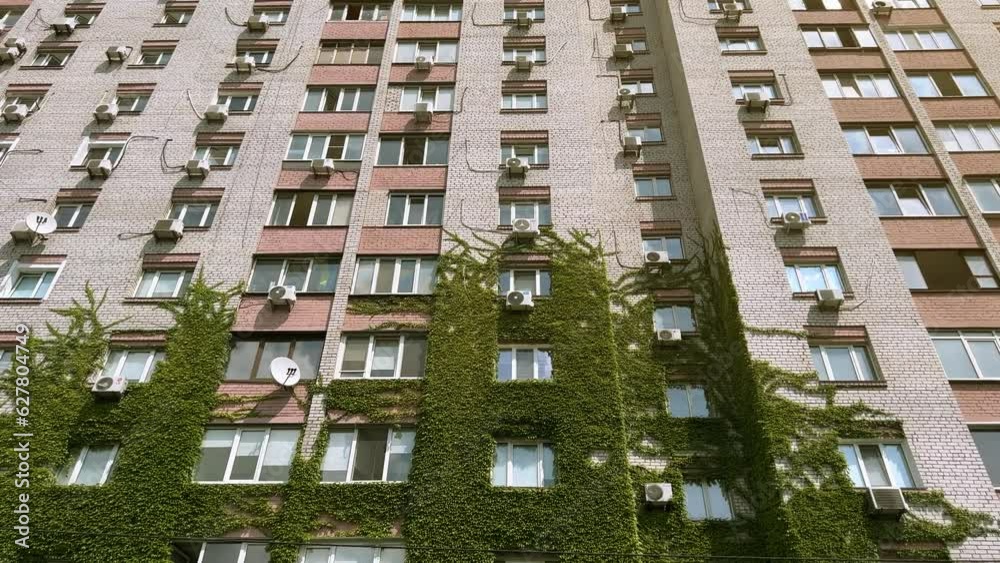 Green building with plants growing on the facade. Wall of a house ...