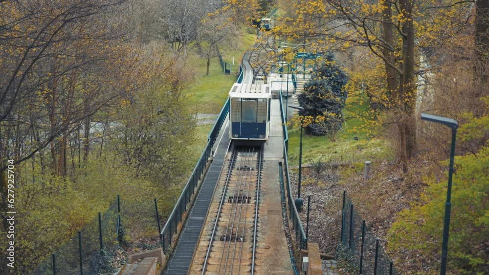 A cable car goes up on Petrin Hill Park in Prague. Green lawns and ...