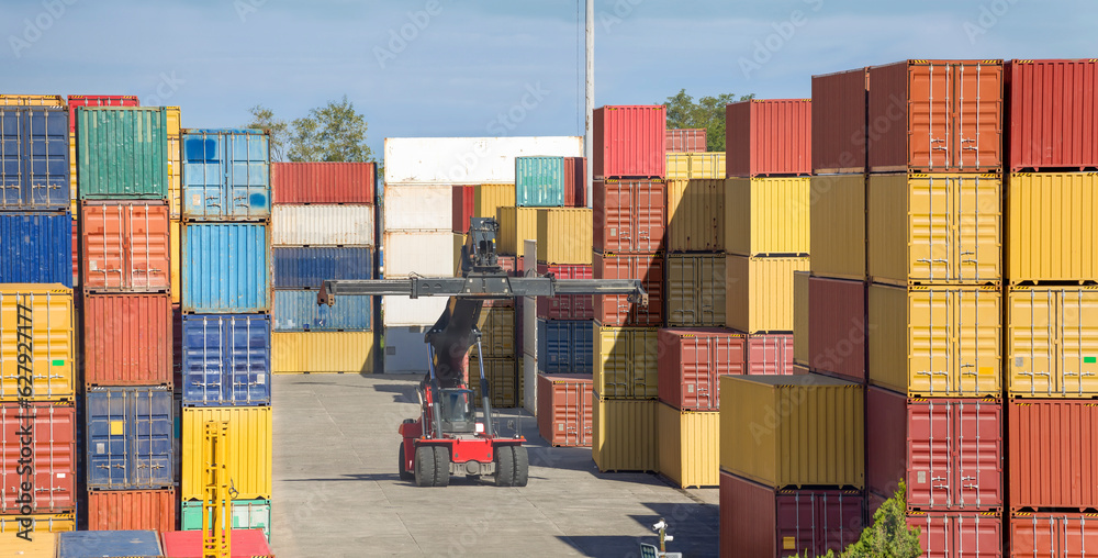 A red stacker drives along the rows of shipping containers at the port ...