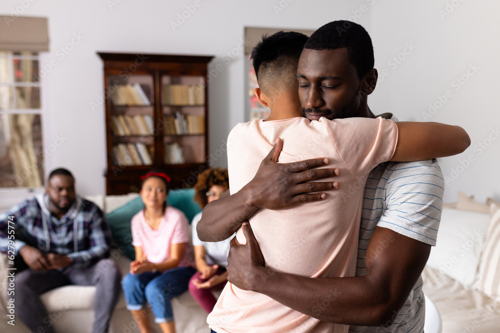 Supportive diverse male friends hugging each other at group therapy ...