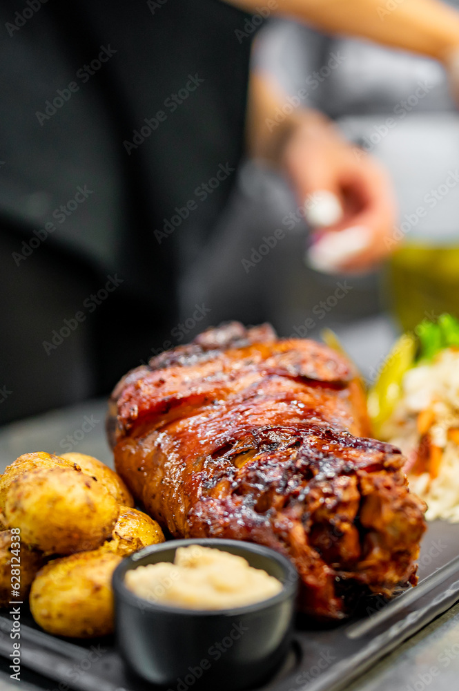 chef hand cooking Baked Pork knuckle with vegetables on plate in ...