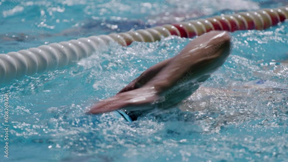 Close-up shot of a muscular professional swimmer swimming in a clean ...