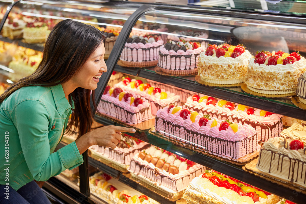 Female customer looking through display case and choosing cake from ...