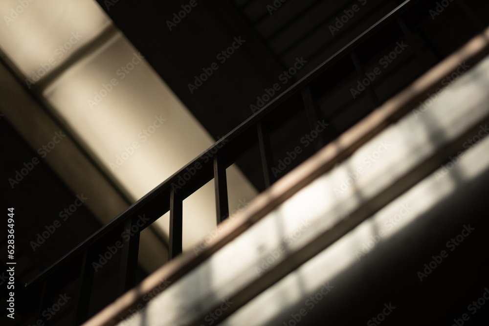 Sunlight from overhead creates dramatic light and shadow on a handrail ...