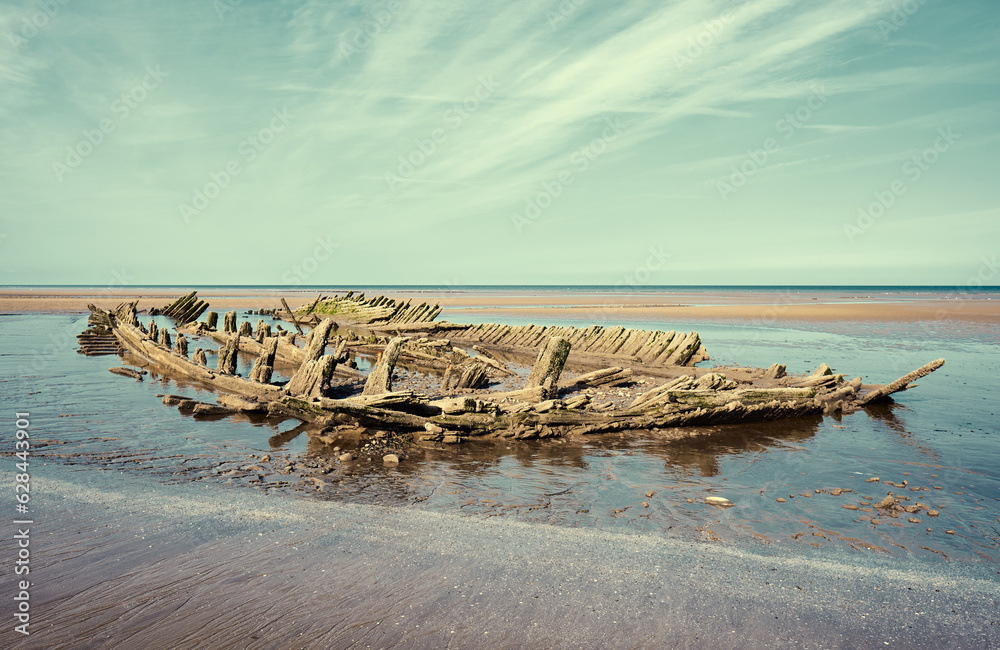 An old historic wooden shipwreck vessel carcass exposed on a desolate ...