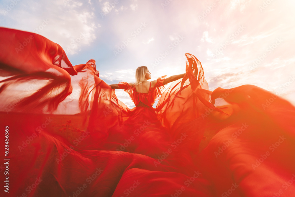 Woman Red Flying Dress. A blonde in a red dress against the sky. Rear ...