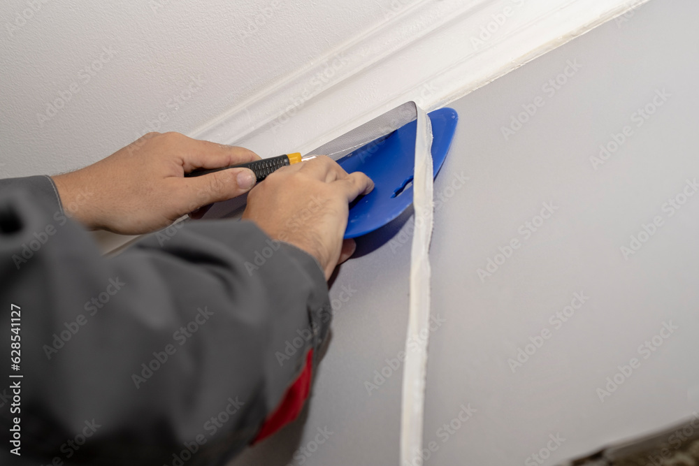 Trimming excess wallpaper. The builder's hands cut the wallpaper. Stock ...