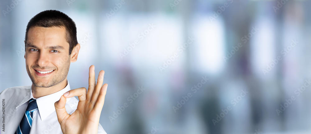 Portrait of smiling businessman in white shirt and tie, showing thumb ...
