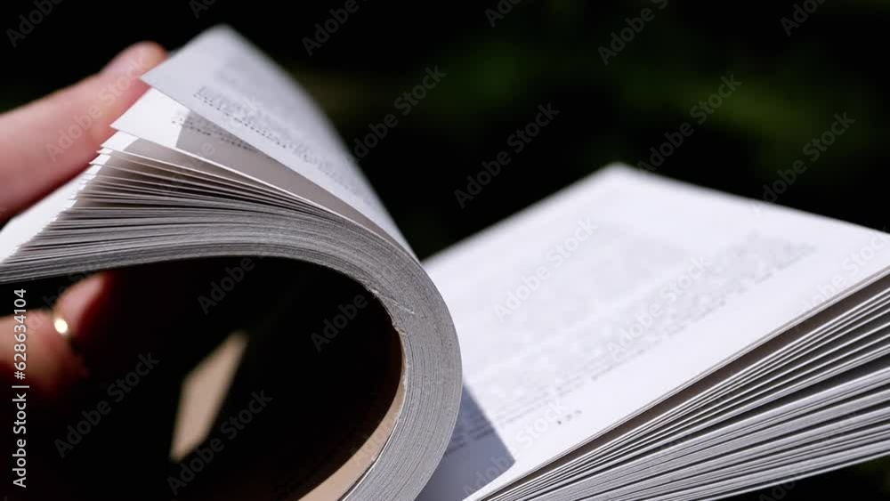 Girl Flipping through the Pages of an Open Book in Nature in Rays of ...