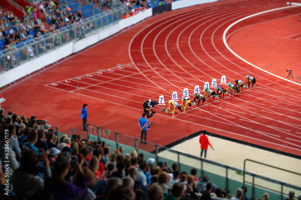 Female Sprinters at the start line of the 100 meters sprint race. Track ...