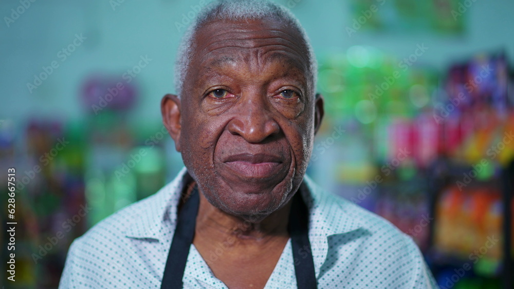 One senior black male employee of supermarket standing inside ...