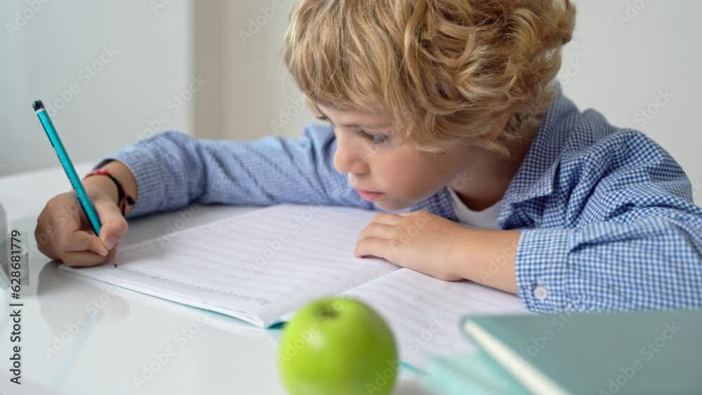 Elementary school student boy or girl writing letters, studying at desk ...