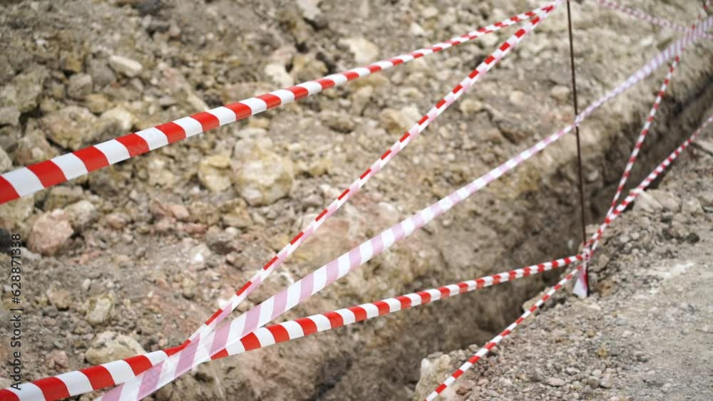 Red white barrier tape trenches. Focus on red and white barrier tape at ...