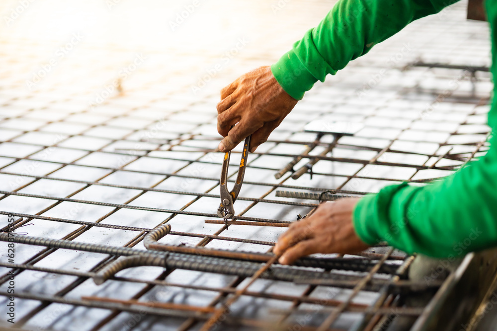 Reinforced concrete structures. Construction worker uses pilers tools ...