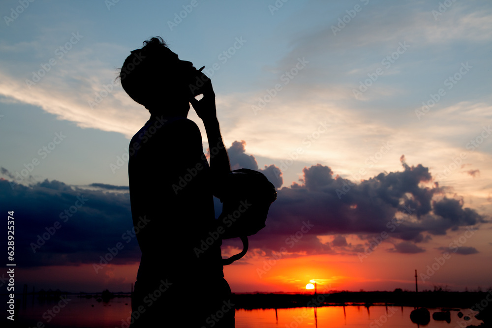 Silueta de hombre fumando en la playa durante el atardecer Stock Photo ...