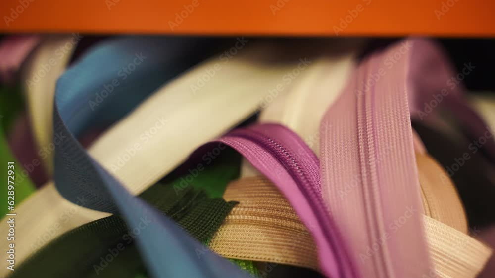 Stack of colourful fabric zippers on the shelf in workshop, zippers of ...