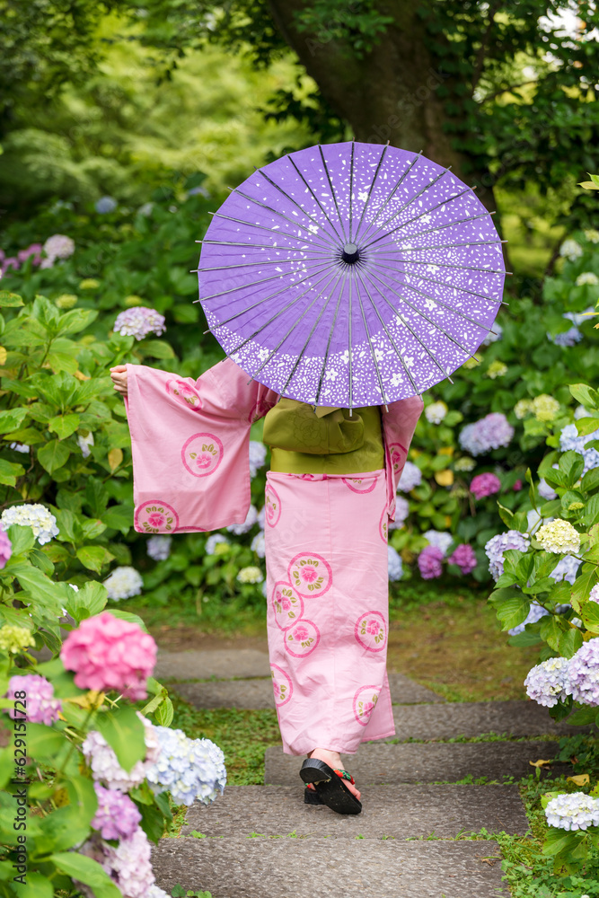Back view of a woman wearing a Japanese bathrobe Yukata and holding a ...
