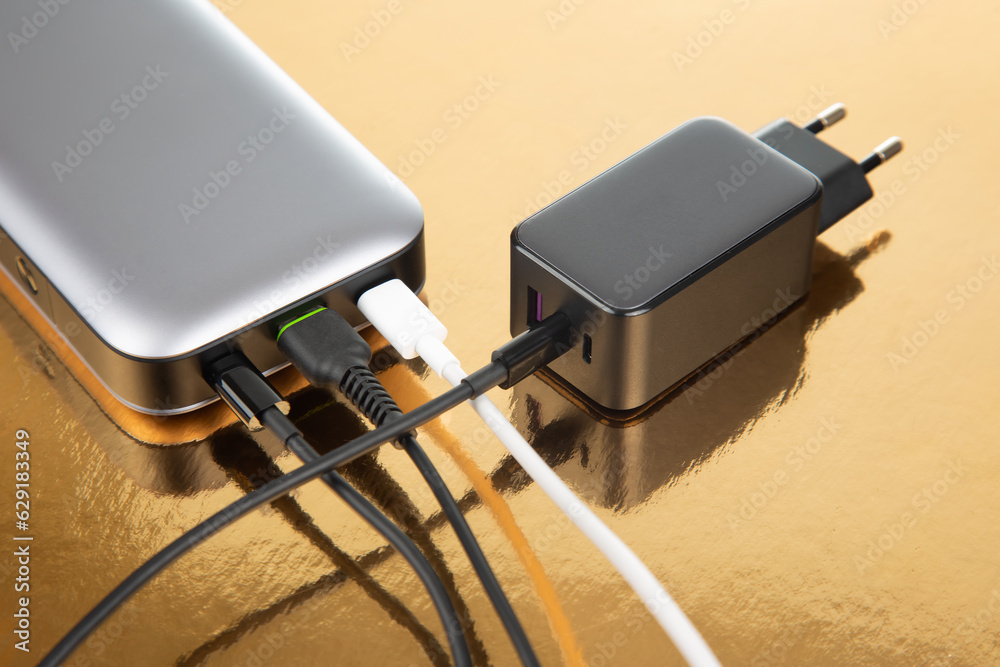 Power bank and charging plug with cable on a golden background ...