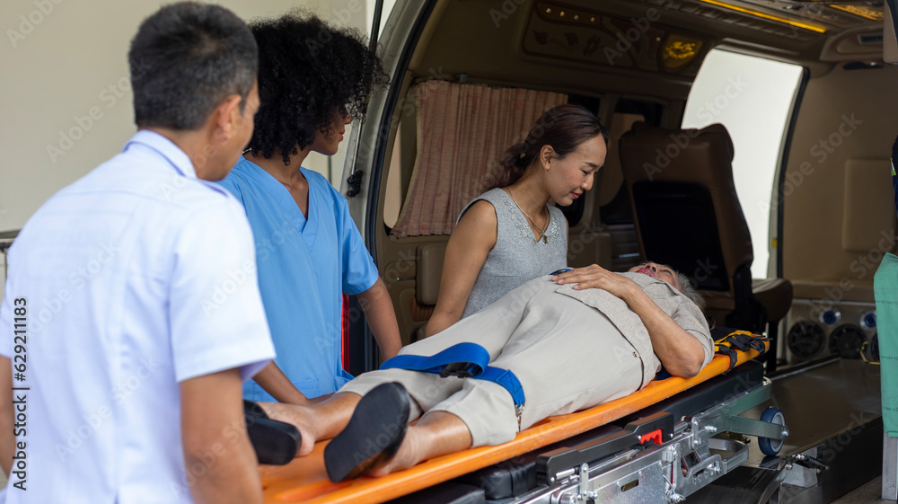 Rescuers using stretcher to move an elderly patient to ambulance van ...