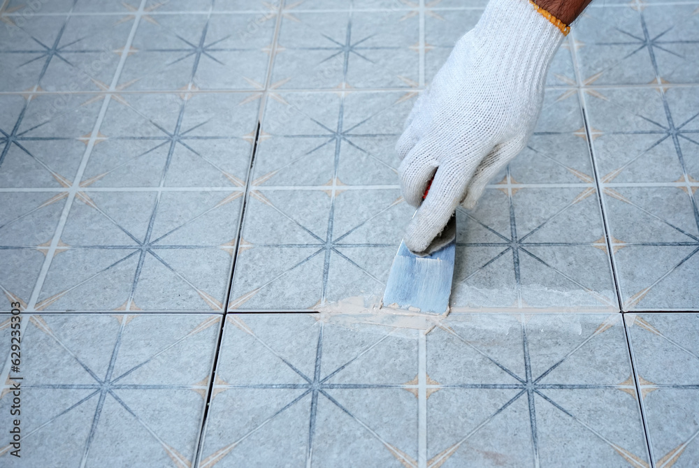 Tiler laying the ceramic tile on the floor. Grouting ceramic tiles ...