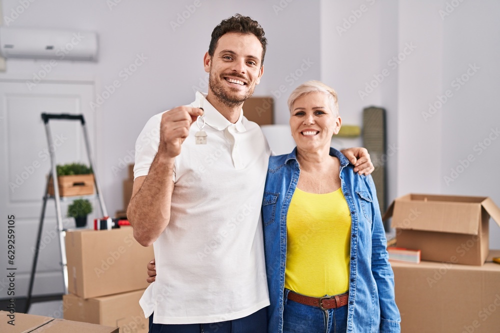 Hispanic mother and son holding keys of new home looking positive and ...