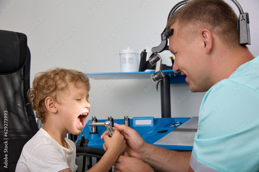 Doctor of the children's hospital checks child's throat using ...